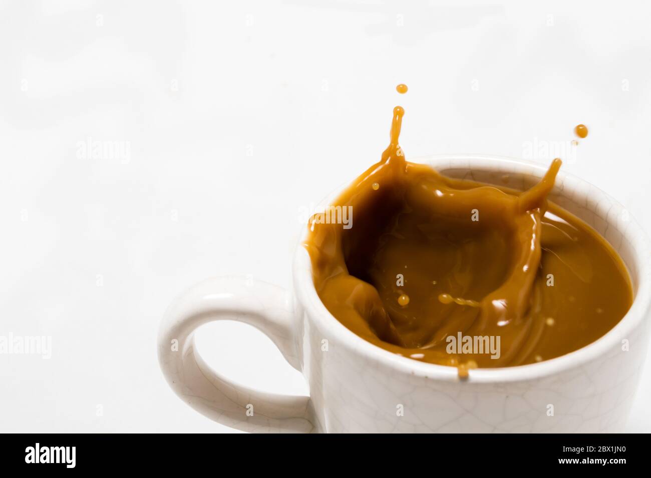 Cup of splashing coffee on white background Stock Photo - Alamy