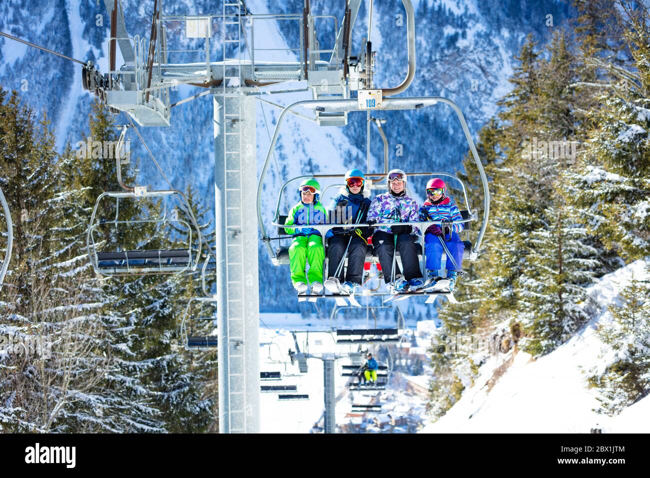Four friends kids sit together on chairlift lifting on the mountain ...