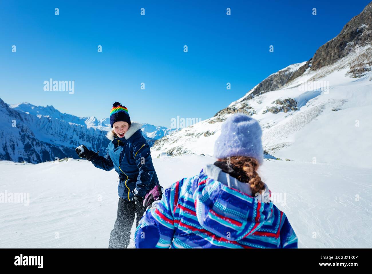 Two girls play snowball fight winter game in the mountains throwing ...