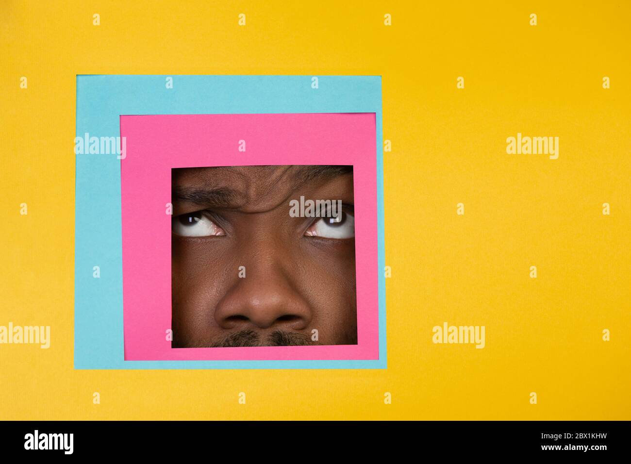 Scared. Face of emotional african-american man peeks throught square in ...
