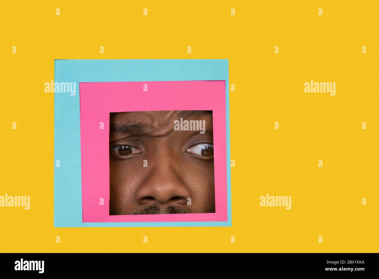 Scared. Face of emotional african-american man peeks throught square in ...