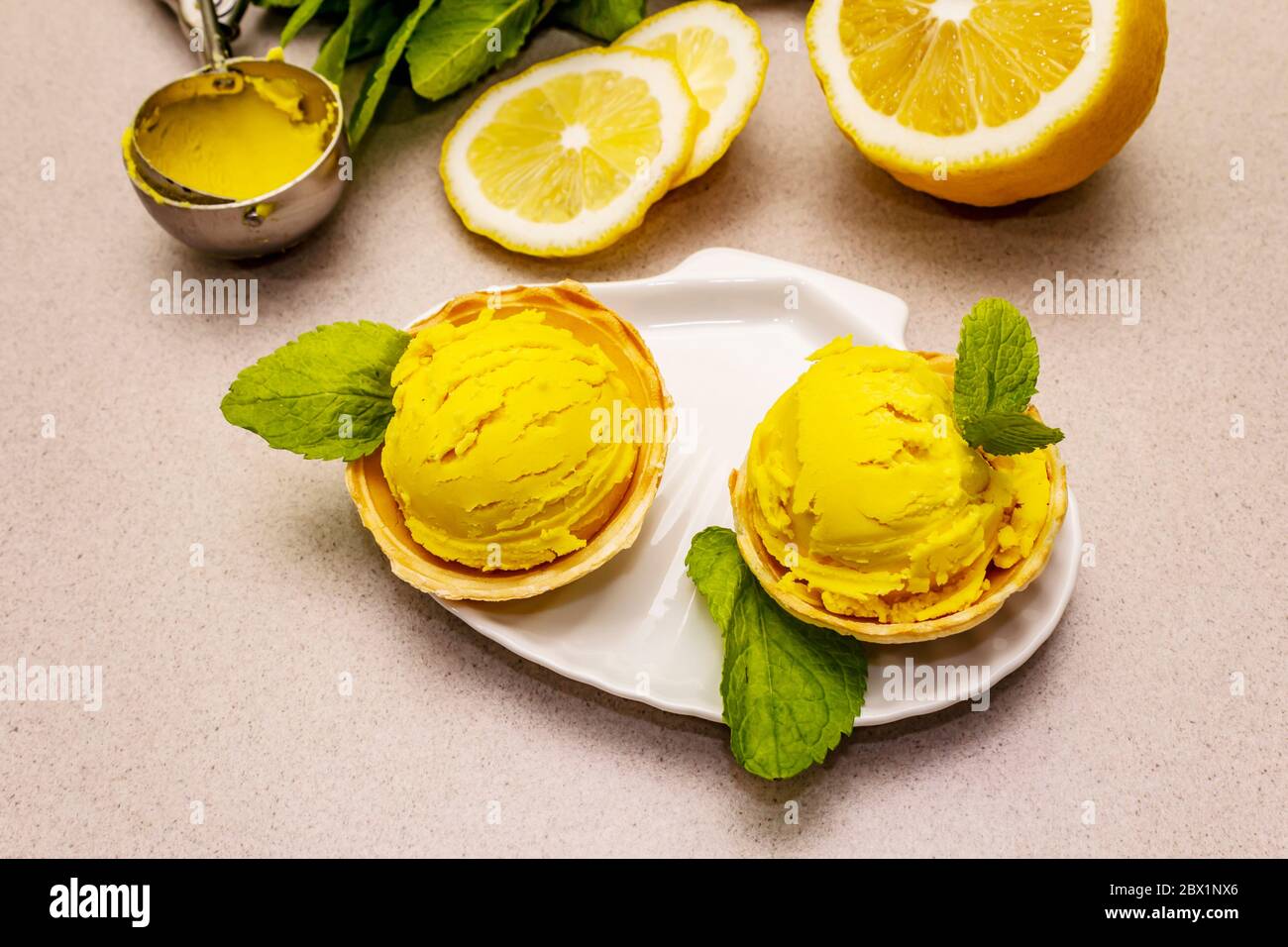 Lemon ice cream with mint. Refreshing summer dessert, ripe fruit, fragrant leaves. Stone ...