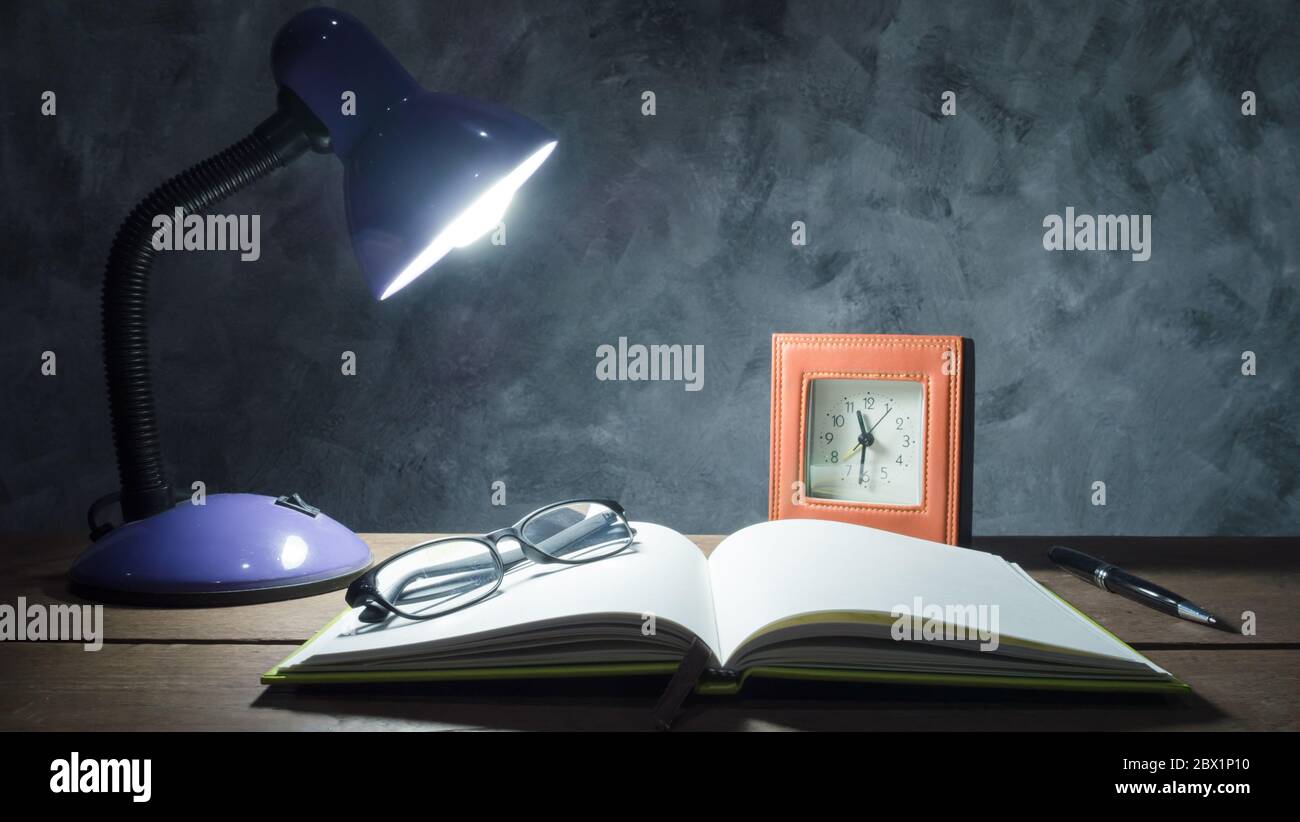 Lamp with notebook,pen,clock and glasses on wooden table with vintage ...