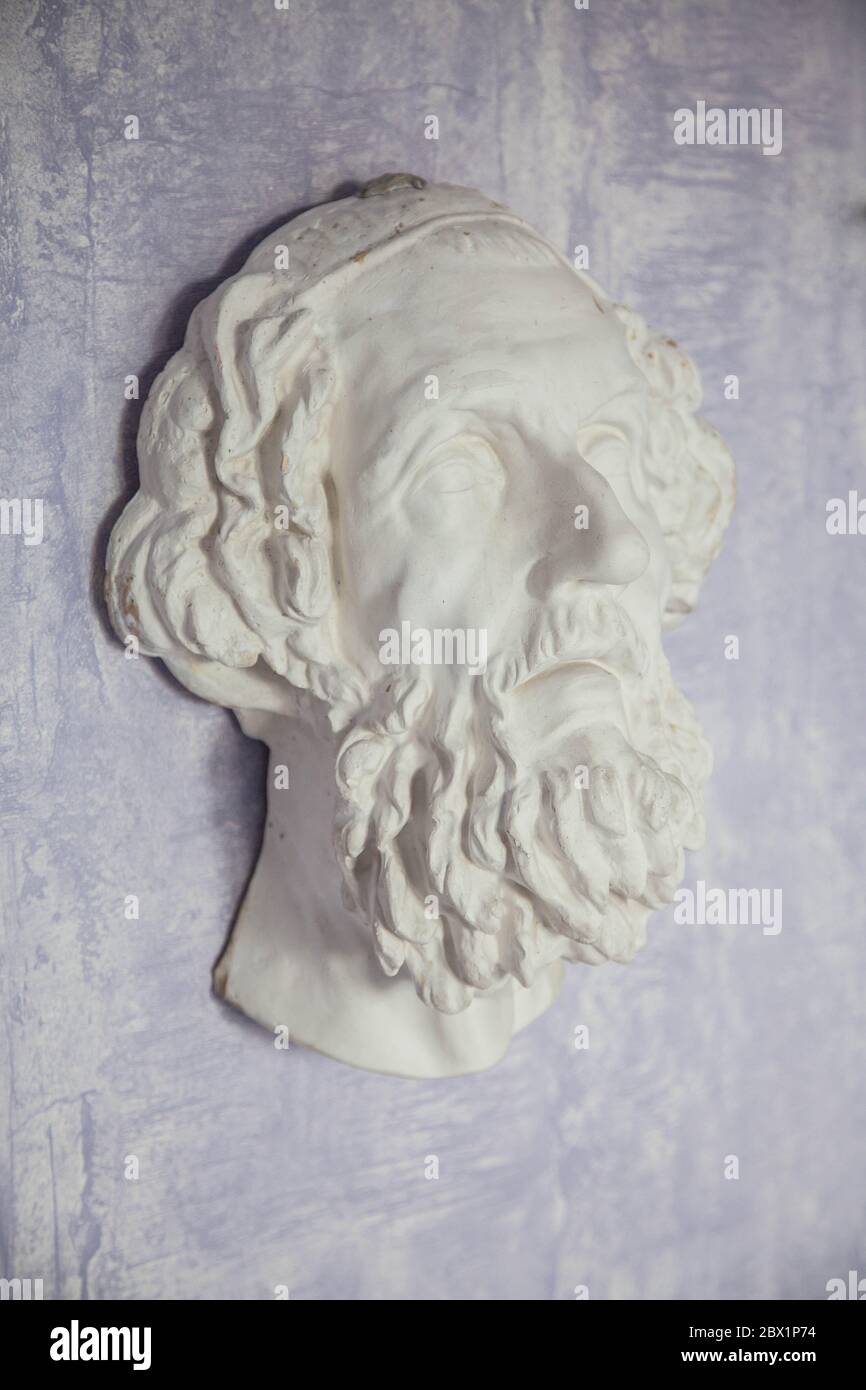 the plaster head of an ancient Greek philosopher looks at the camera ...
