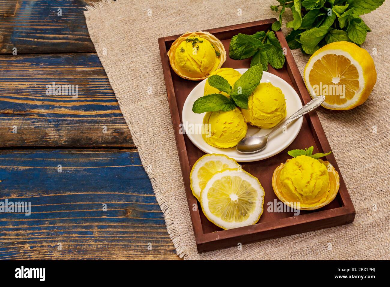 Lemon ice cream with mint. Refreshing summer dessert, ripe fruit, fragrant leaves. Wooden boards ...