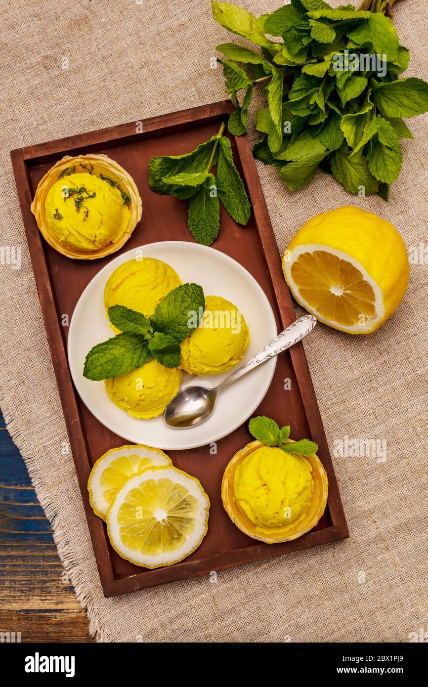 Lemon ice cream with mint. Refreshing summer dessert, ripe fruit, fragrant leaves. Wooden boards ...