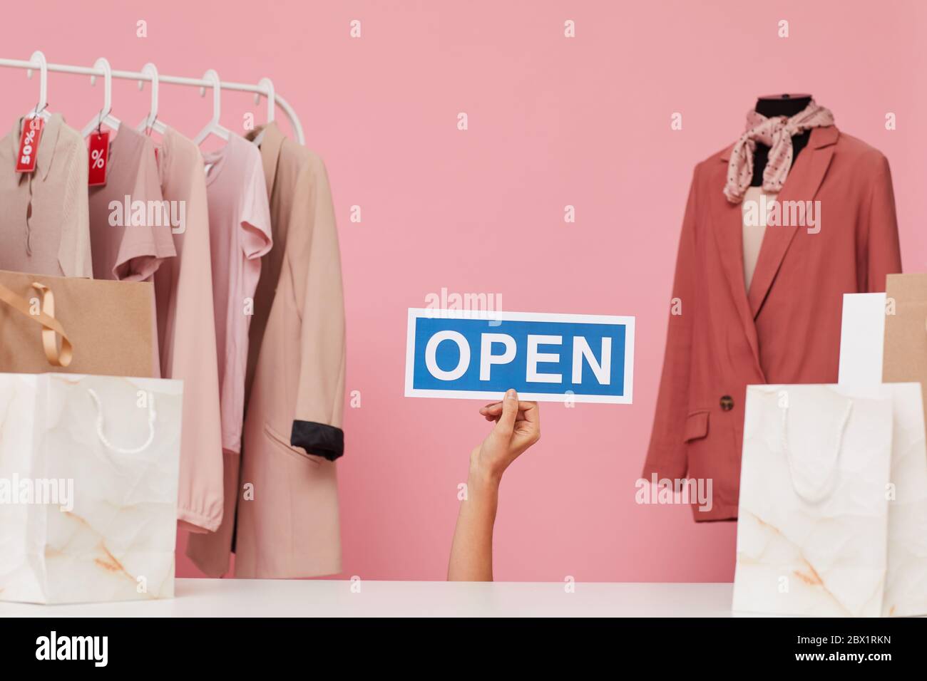 Image of female hand holding placard with Open sign in the clothes shop ...