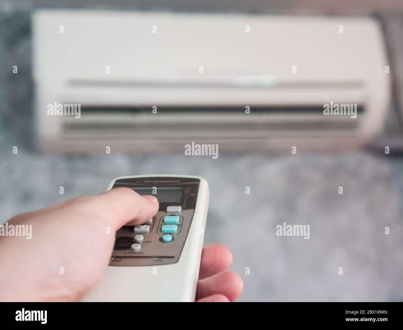 Hand holding remote in front of air conditioner Stock Photo - Alamy