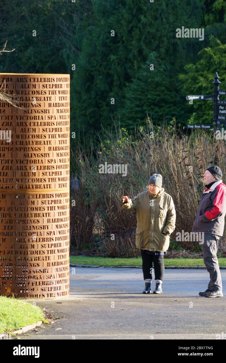 A man & woman looking at steel sculpted light installation with carved ...