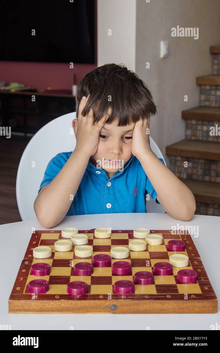 Smart child playing checkers at the table against an opponent Stock ...