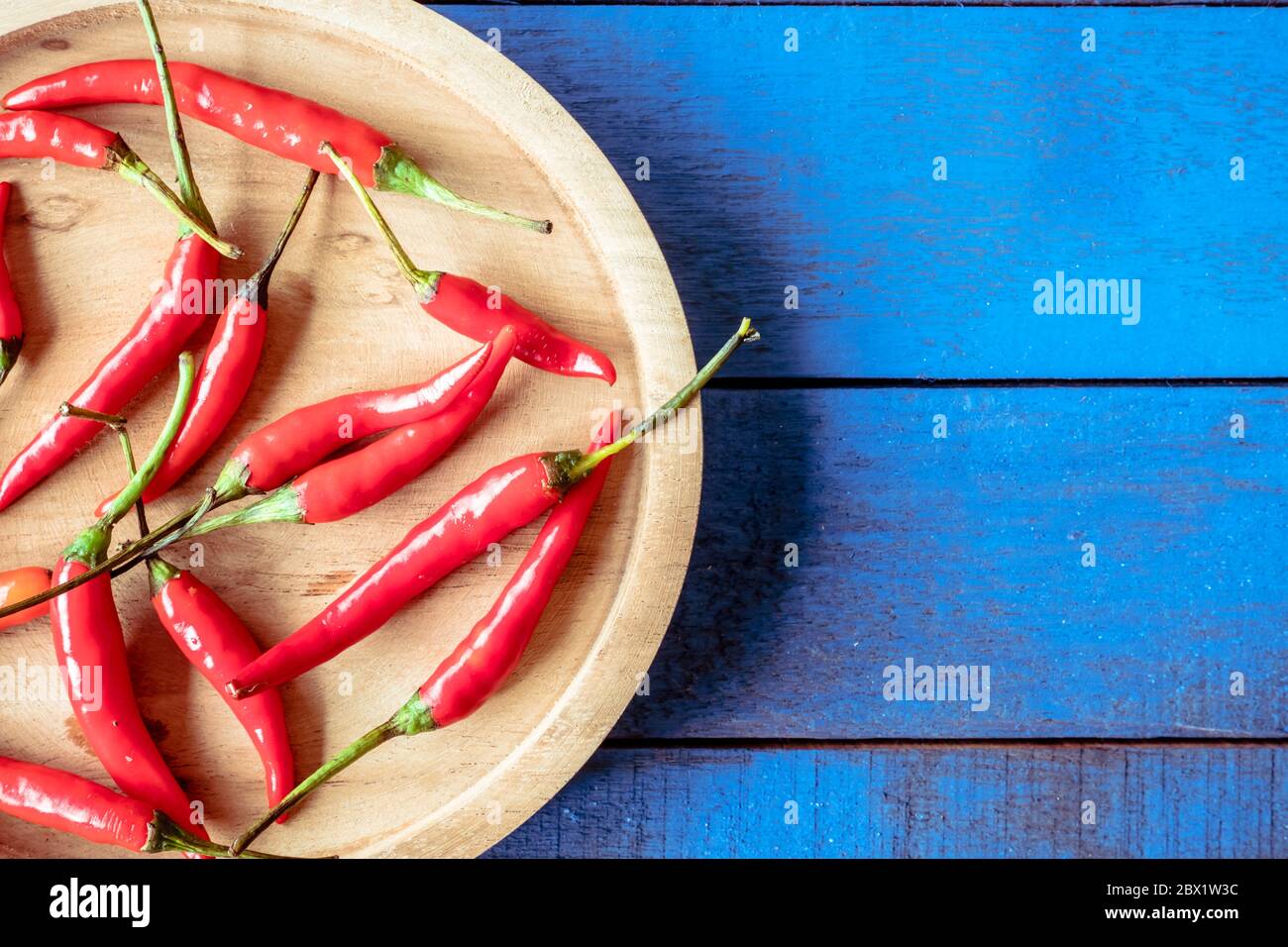 Top view of Red hot chilli peppers on tray over blue wooden table ...