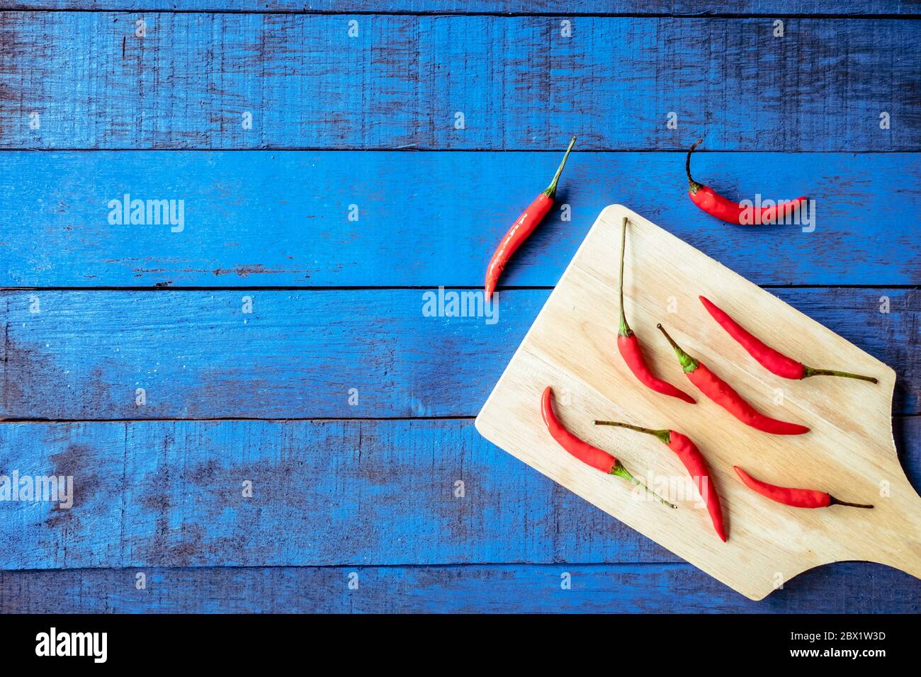 Top view of Red hot chilli peppers on tray over blue wooden table ...