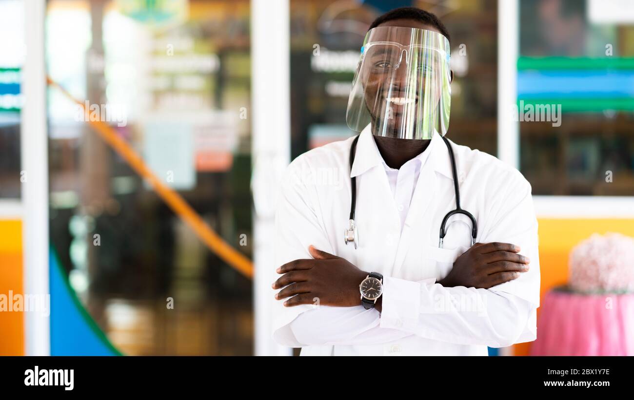 African doctor wear face shield and holding stethoscope with kind and ...