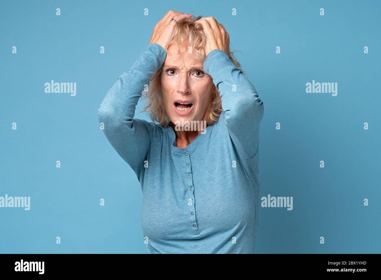 Mature woman holding head in hands feels unhealthy Stock Photo - Alamy
