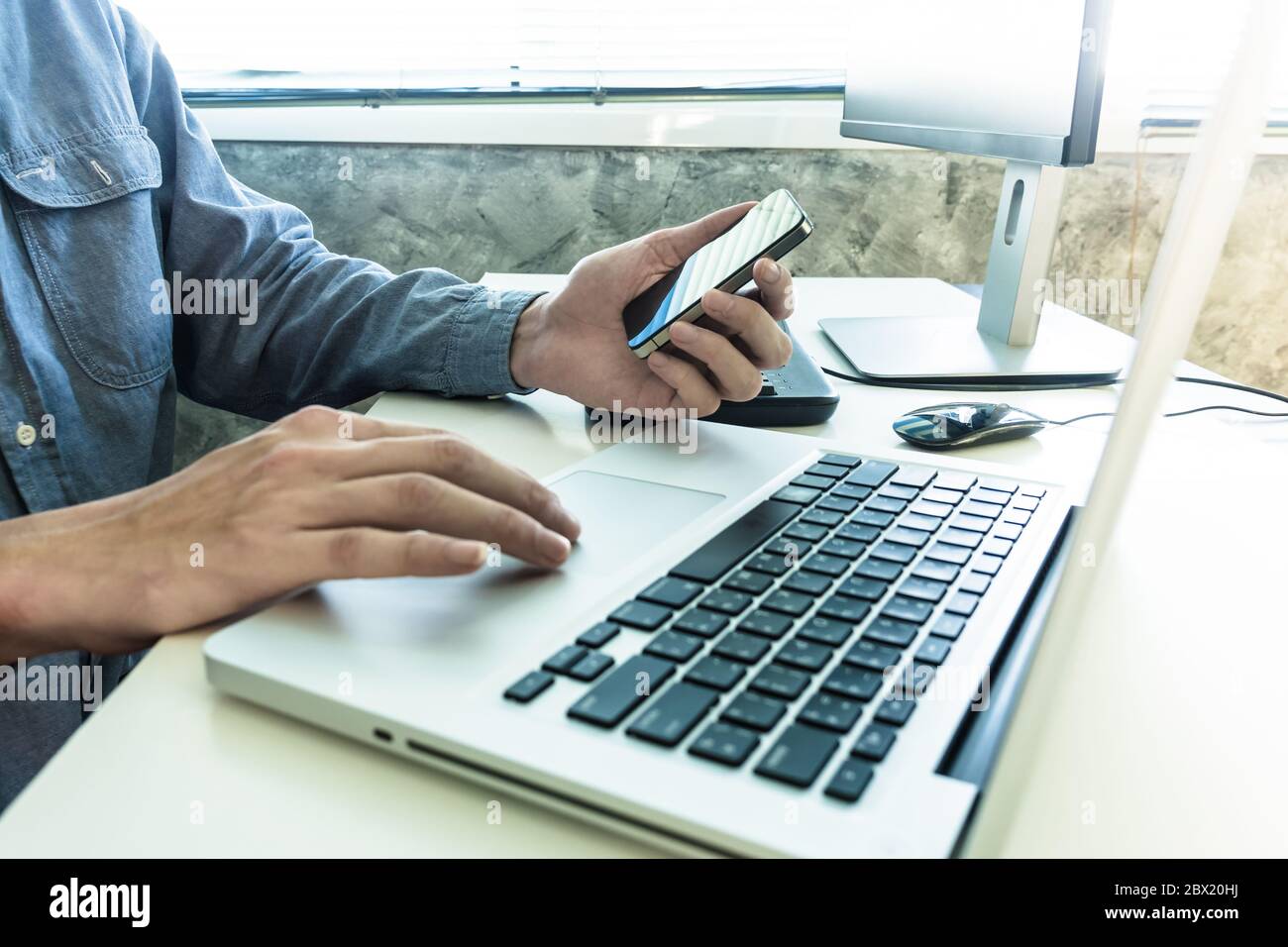 Male hands using smart phone with computer on the desk Stock Photo - Alamy