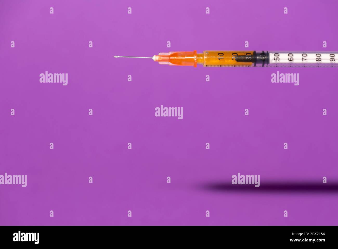 Syringe for vaccine or insulin, with its shadow, on a purple background ...