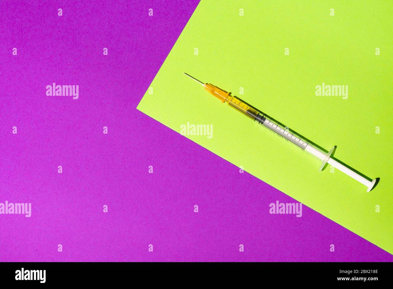 Syringe for vaccine or insulin, with its shadow, on a purple and yellow ...