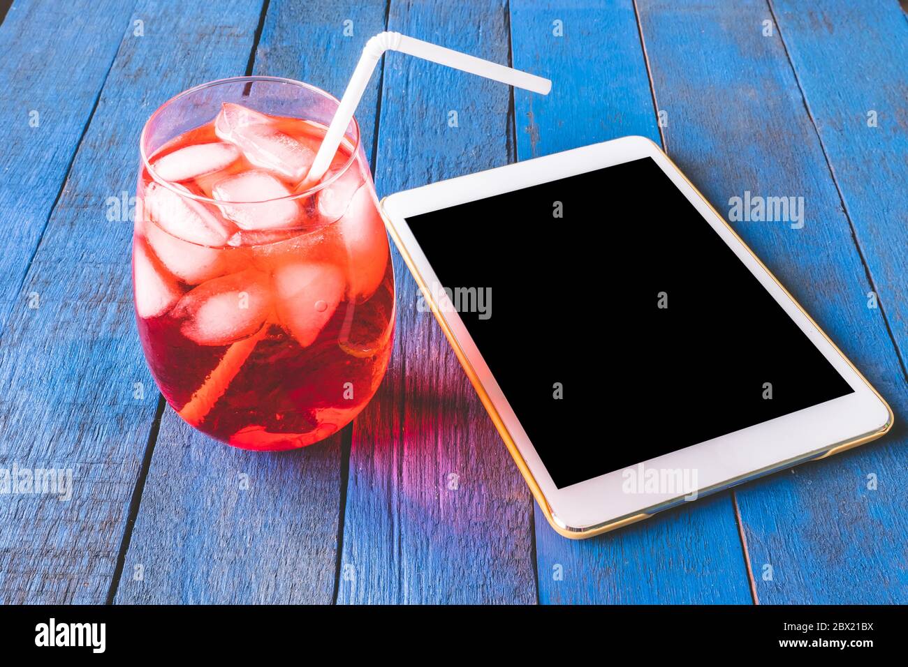 Tablet and red cocktail on blue painted wood plank background Stock ...