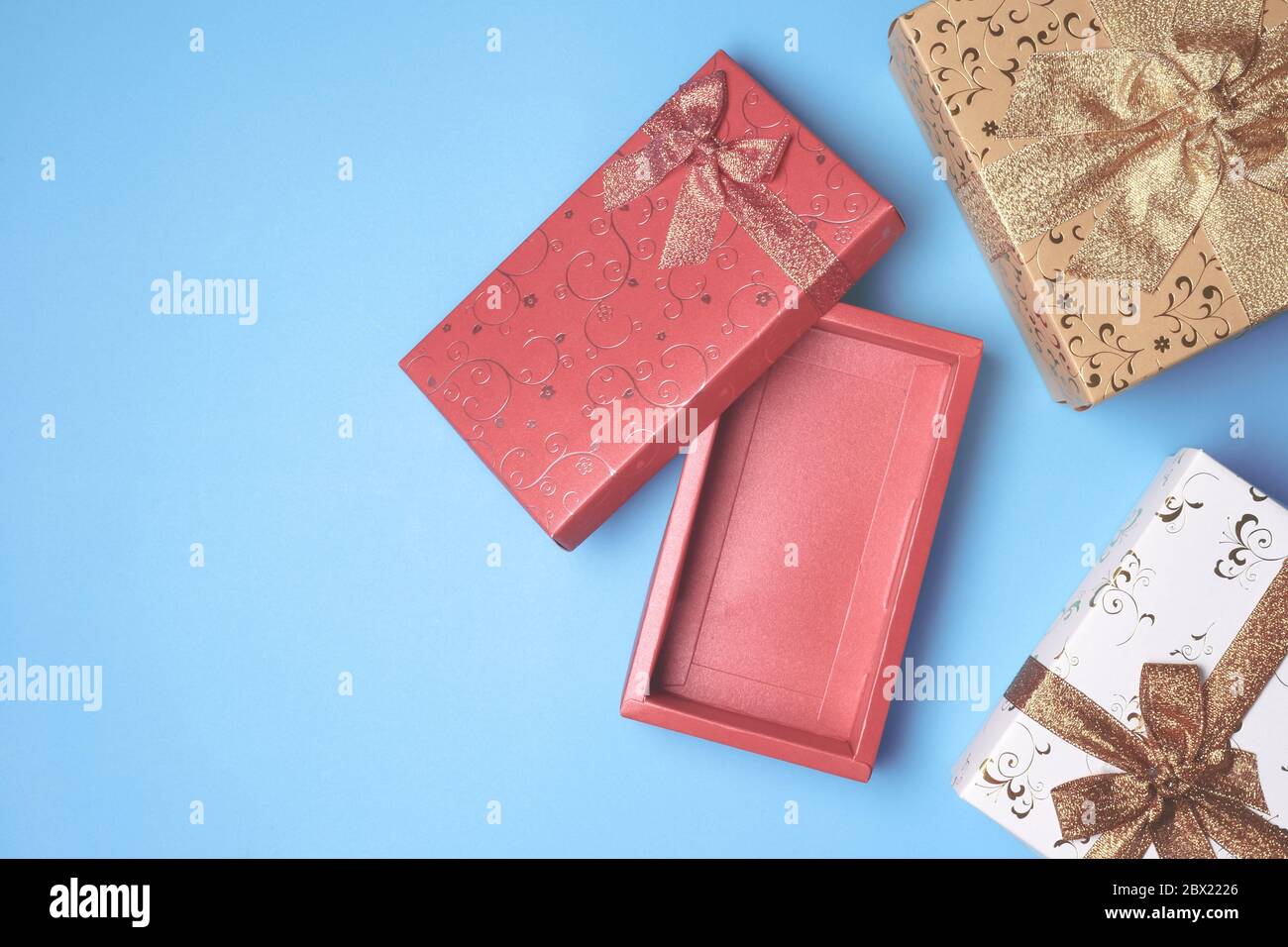 Top view of open red gift box and presents on blue background. Free ...