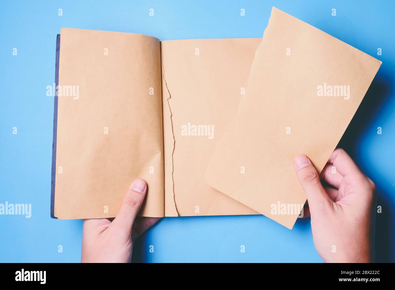 Top view of hands tear paper in notebook on blue background Stock Photo ...