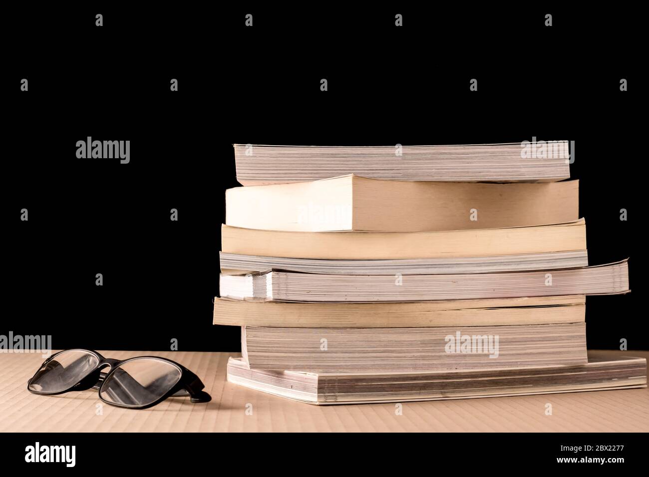 Stack of books and eyeglasses on wooden table, Black background Stock ...