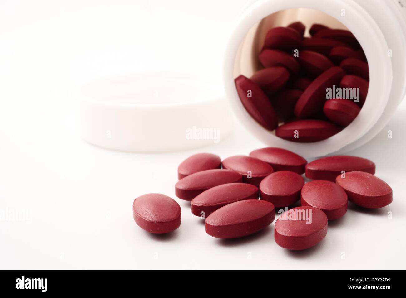 Red vitamin pills pouring out of the bottle on white background Stock ...