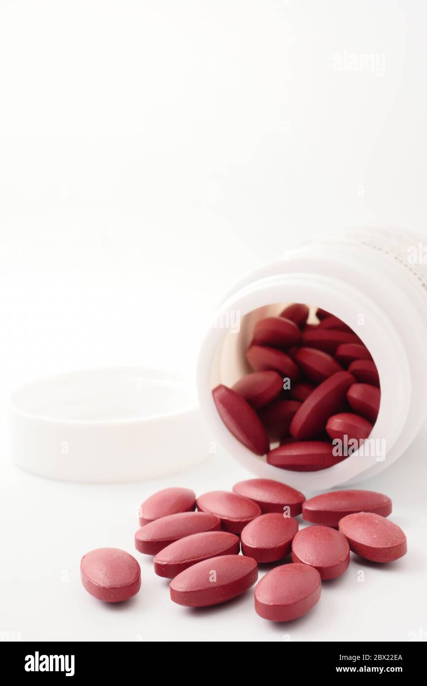 Red vitamin pills pouring out of the bottle on white background Stock ...