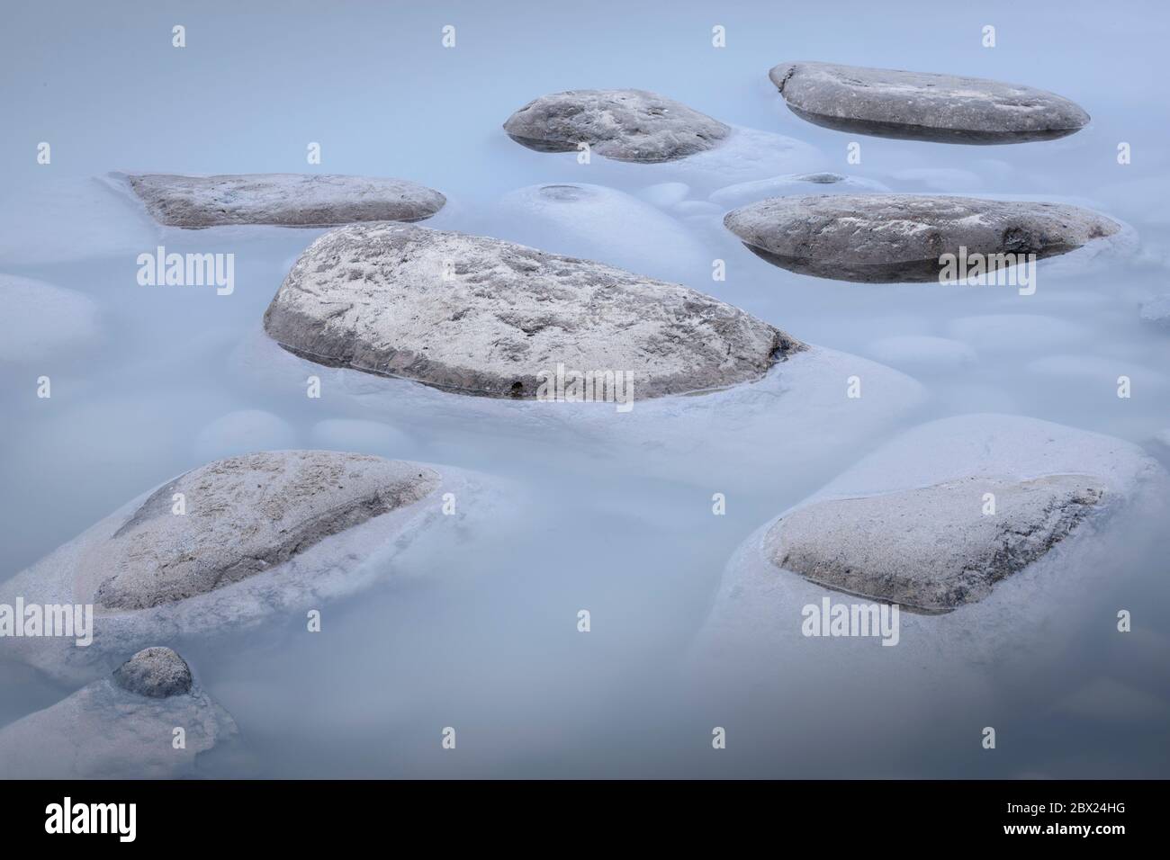 A group of partially submerged rocks in a shallow pool of water on ...
