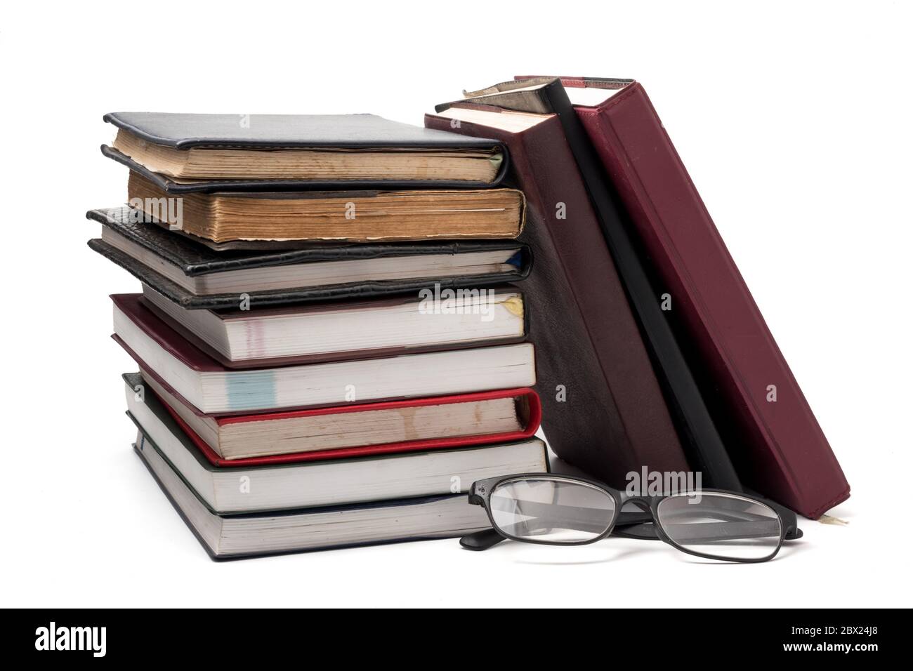 A stack of books with eyeglasses on a white background Stock Photo - Alamy