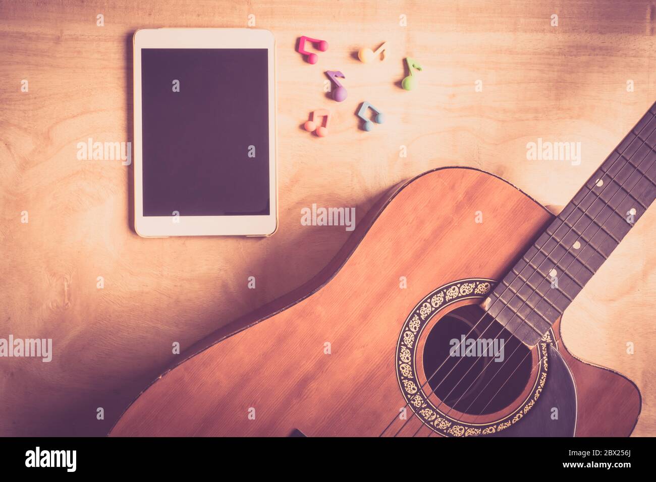 Top view of acoustic guitar with tablet touch computer gadget on wooden ...