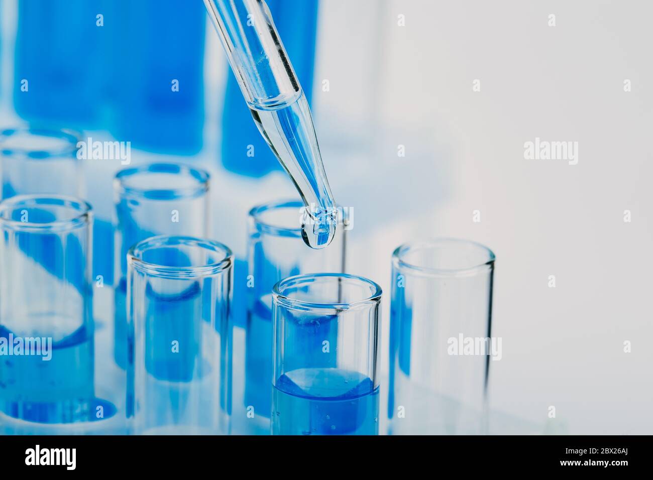 Laboratory glassware with a dropper dripping liquid into a test tube ...