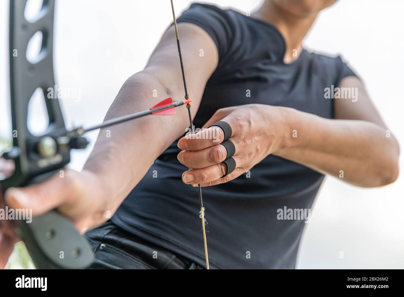 attractive spot woman stretching a bow string with an arrow on archery ...