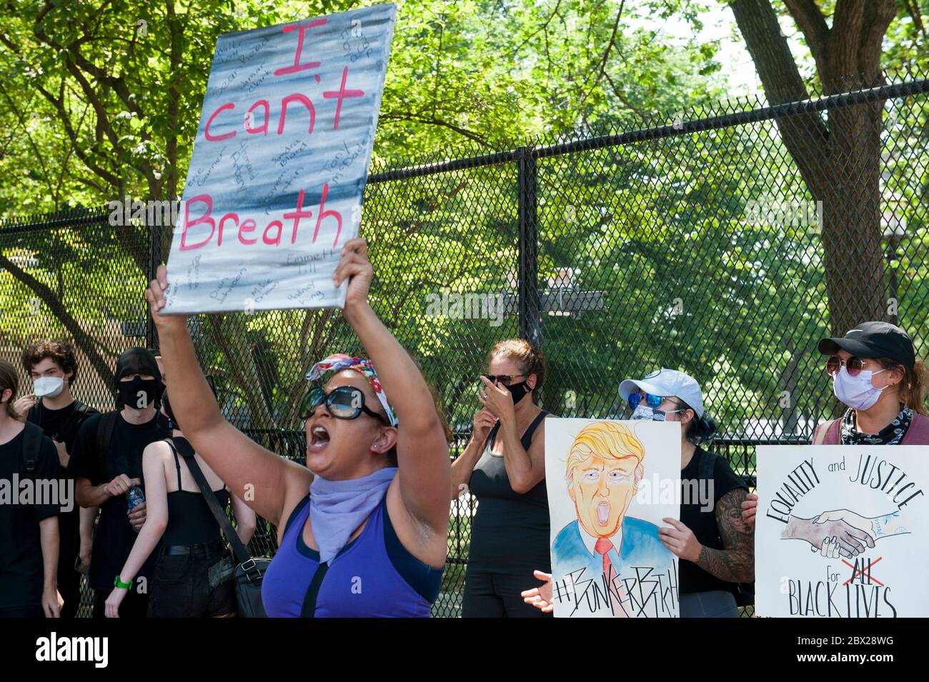 A small group of about 60 protestors stand along the chain link fence ...