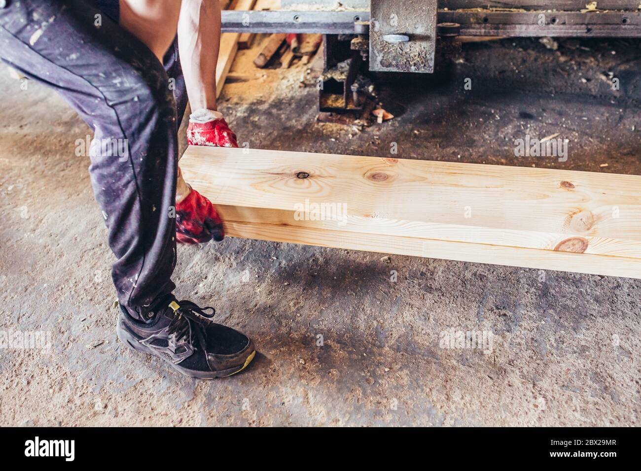 A worker at the sawmill raises the boards with his hands - the conveyor ...