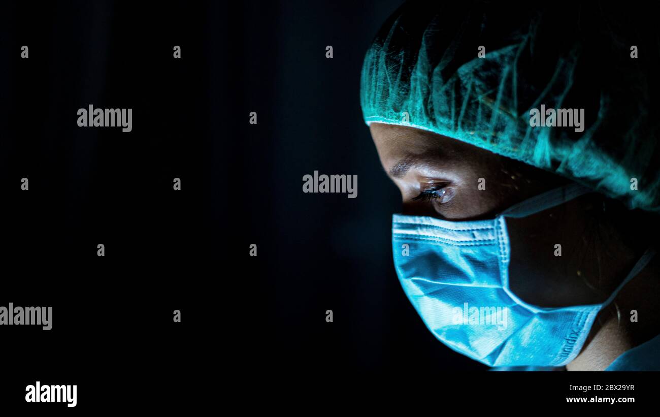 Portrait of young female surgeon, wearing mask and a surgical mask, in ...