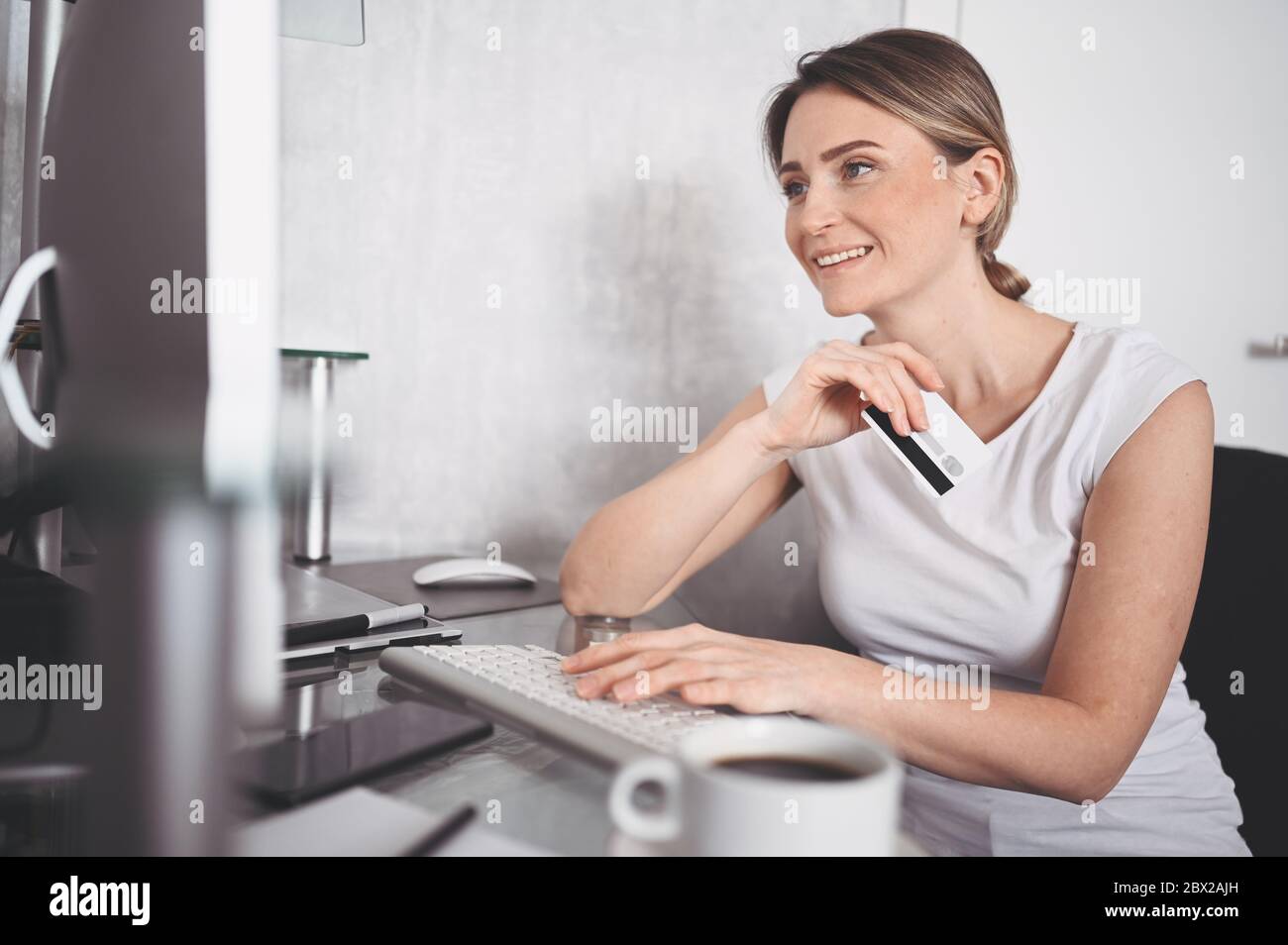 Beautiful happy woman holding credit card in hand and using laptop ...