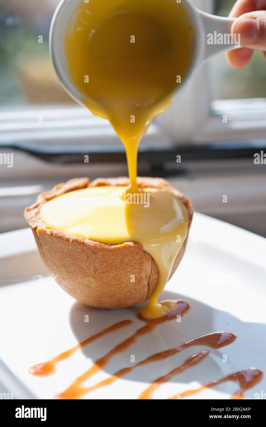 custard poured over apple tart at British pub Stock Photo - Alamy