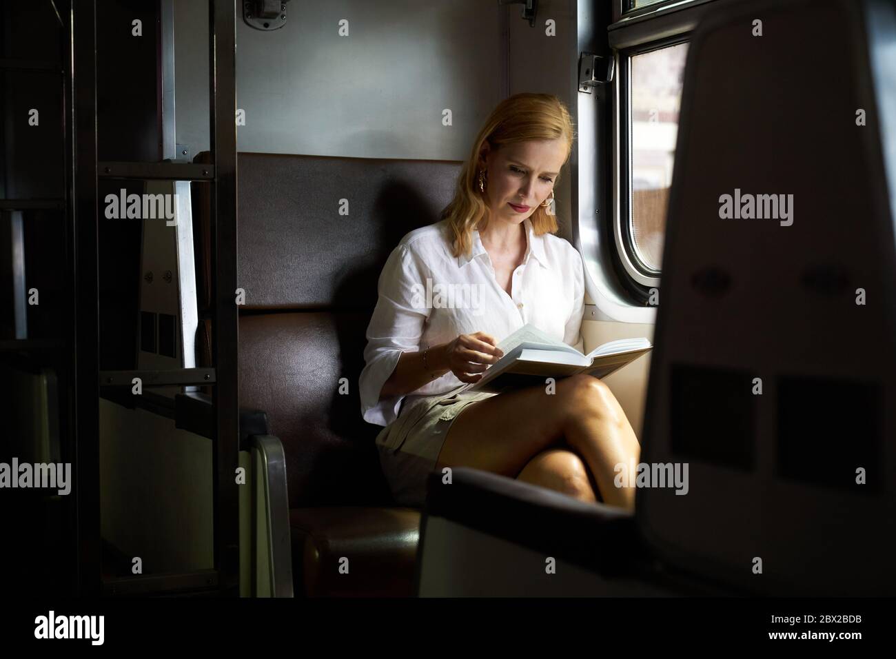 A woman reading a book on a train Stock Photo - Alamy