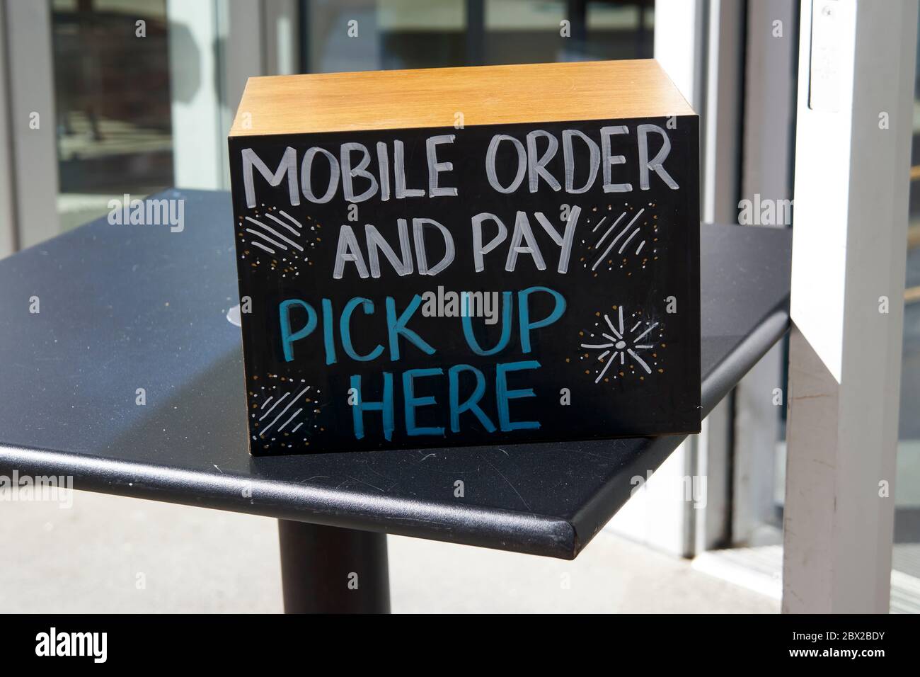 A mobile order and pay pick up sign on a table outside a coffee shop ...