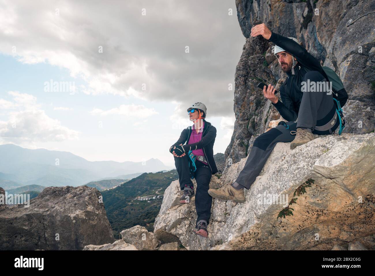Concept: adventure. Man and woman climbers with helmet and harness ...