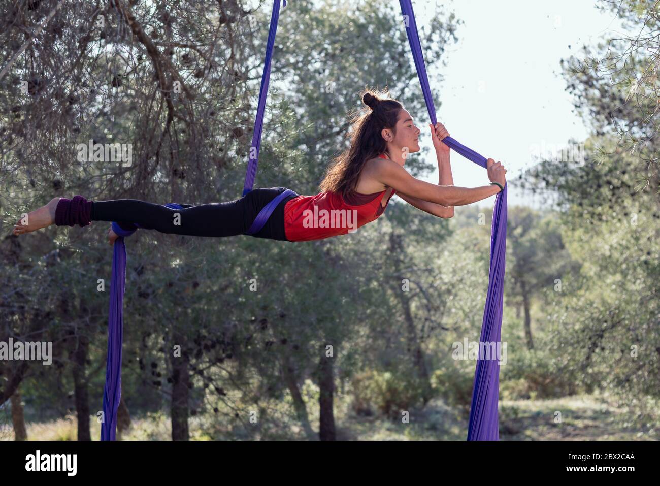 Young girl acrobat. Practicing aerial silks. Strong woman doing stunts ...
