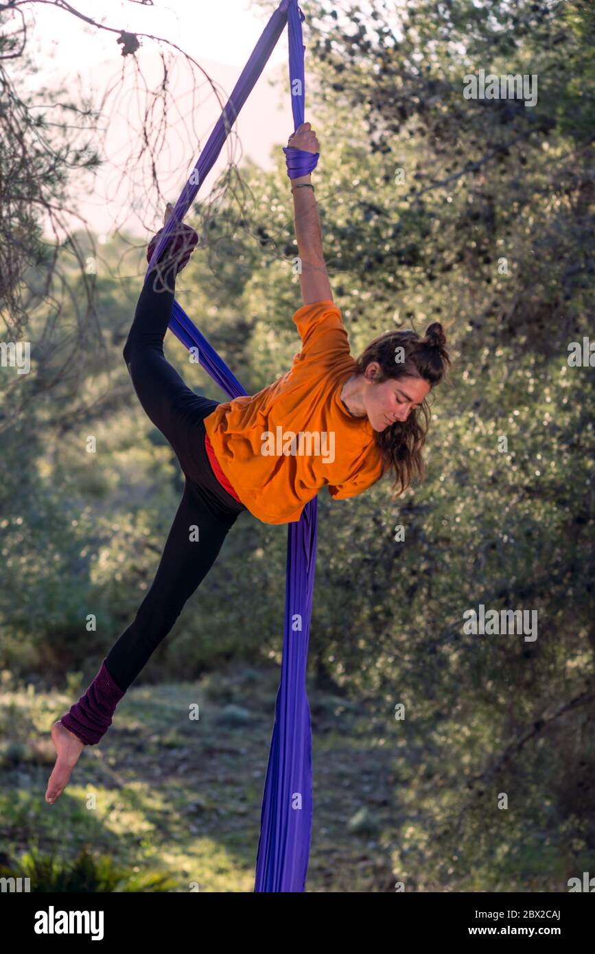 Young girl acrobat. Practicing aerial silks. Strong woman doing circus ...