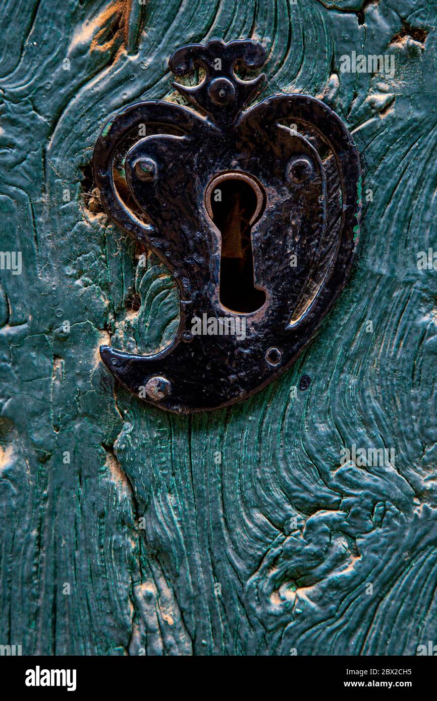 Old heart shaped door lock on a textured wooden door painted in blue ...