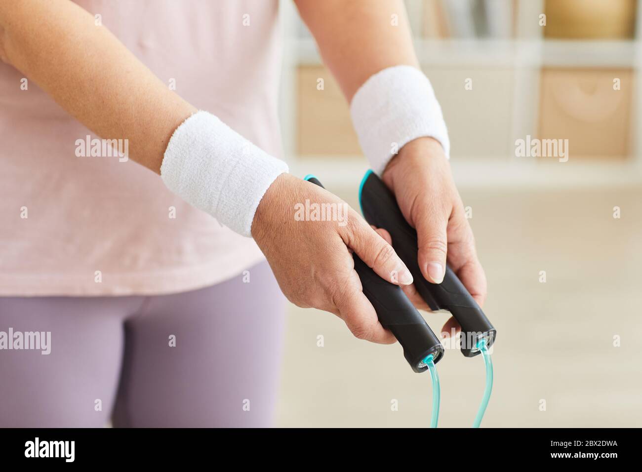 Woman exercising with skipping rope. Close-up of senior woman holding ...