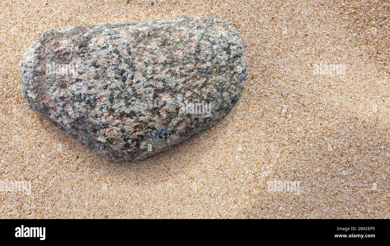 Rock in sand Stock Photo - Alamy