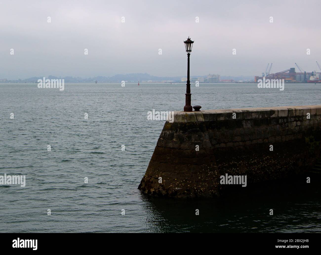 Solitary traditional design lamp post at the end of a sea wall ...