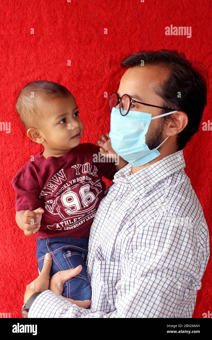 father wearing surgical mask on face and carry his baby son playing ...