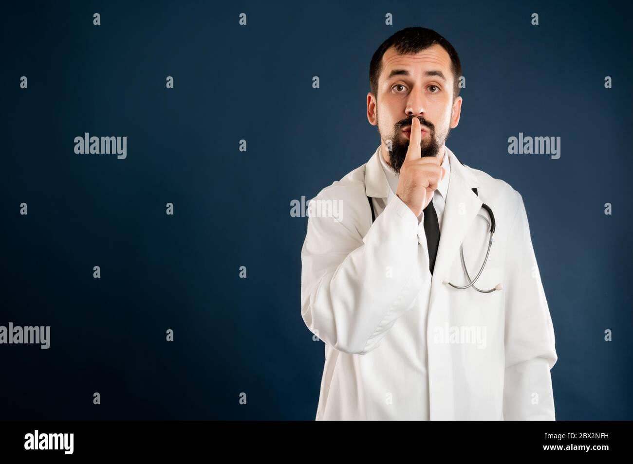 Portrait of male doctor with stethoscope in medical uniform showing shh ...