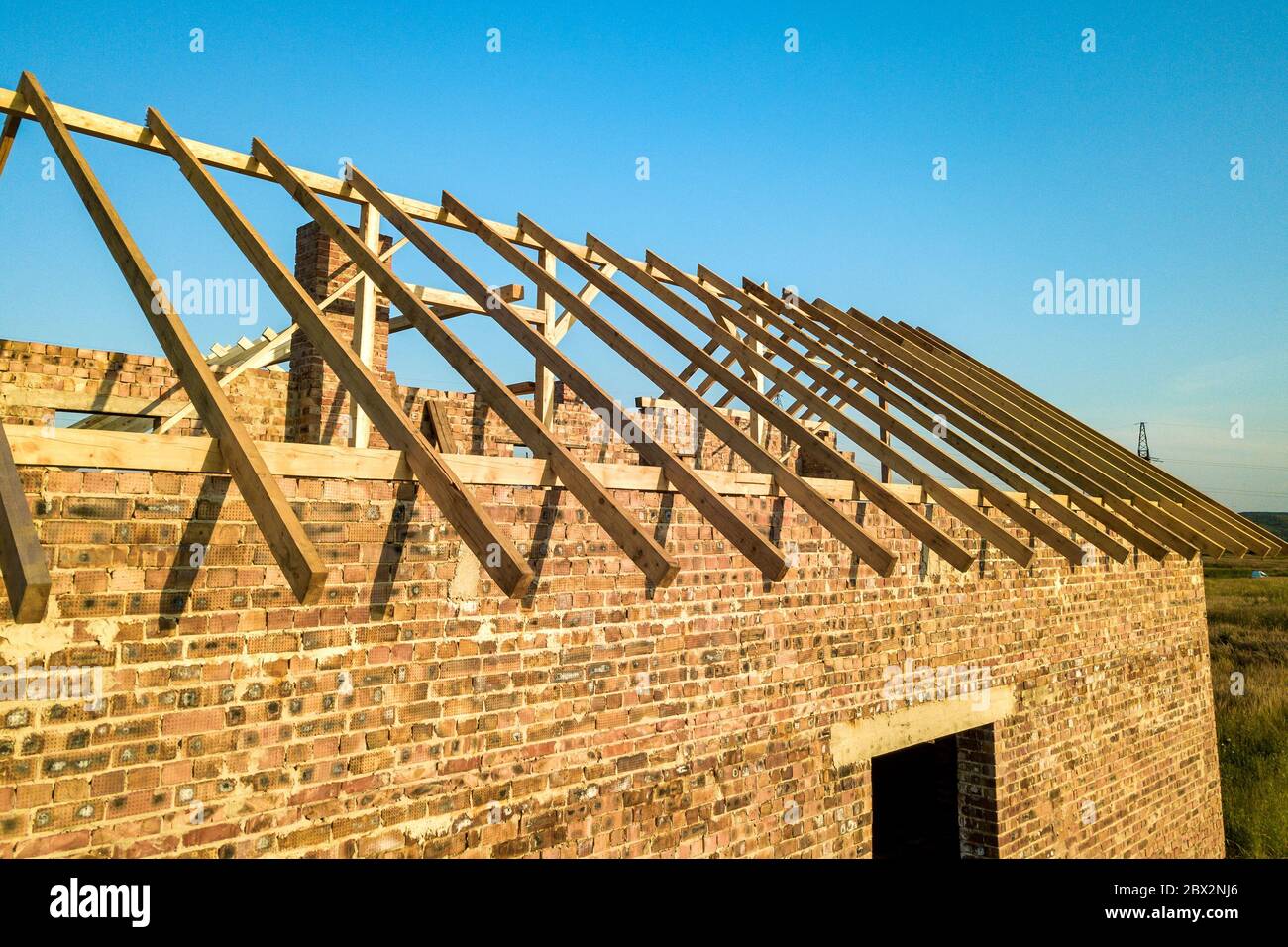 Unfinished brick house with wooden roof structure under construction ...