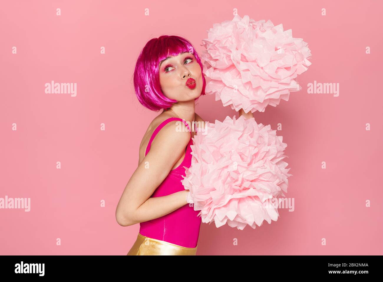 Image of amusing woman in wig making kiss lips and dancing with pom ...